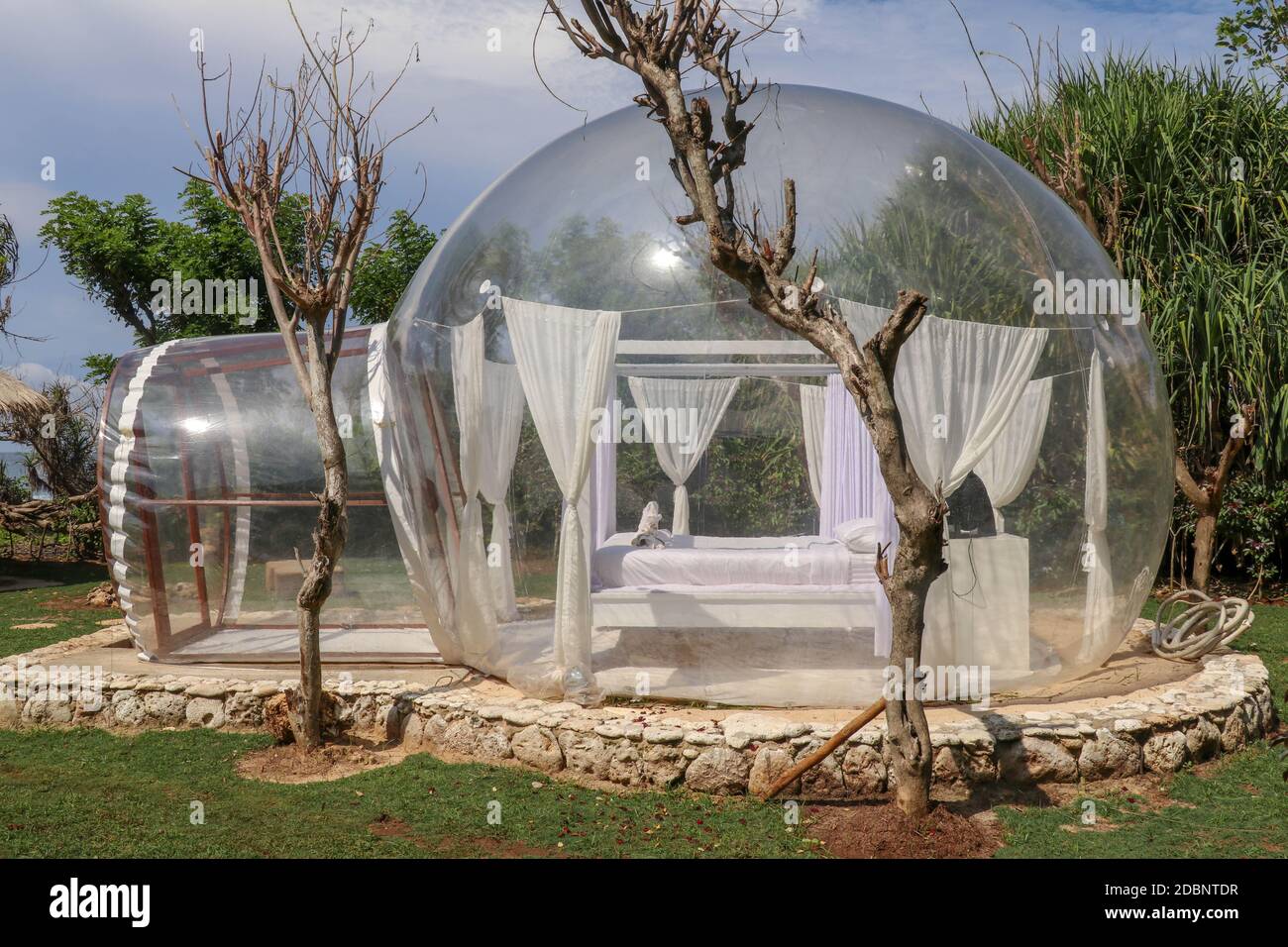 Bubble house with transparent walls. White wooden double bed with ...