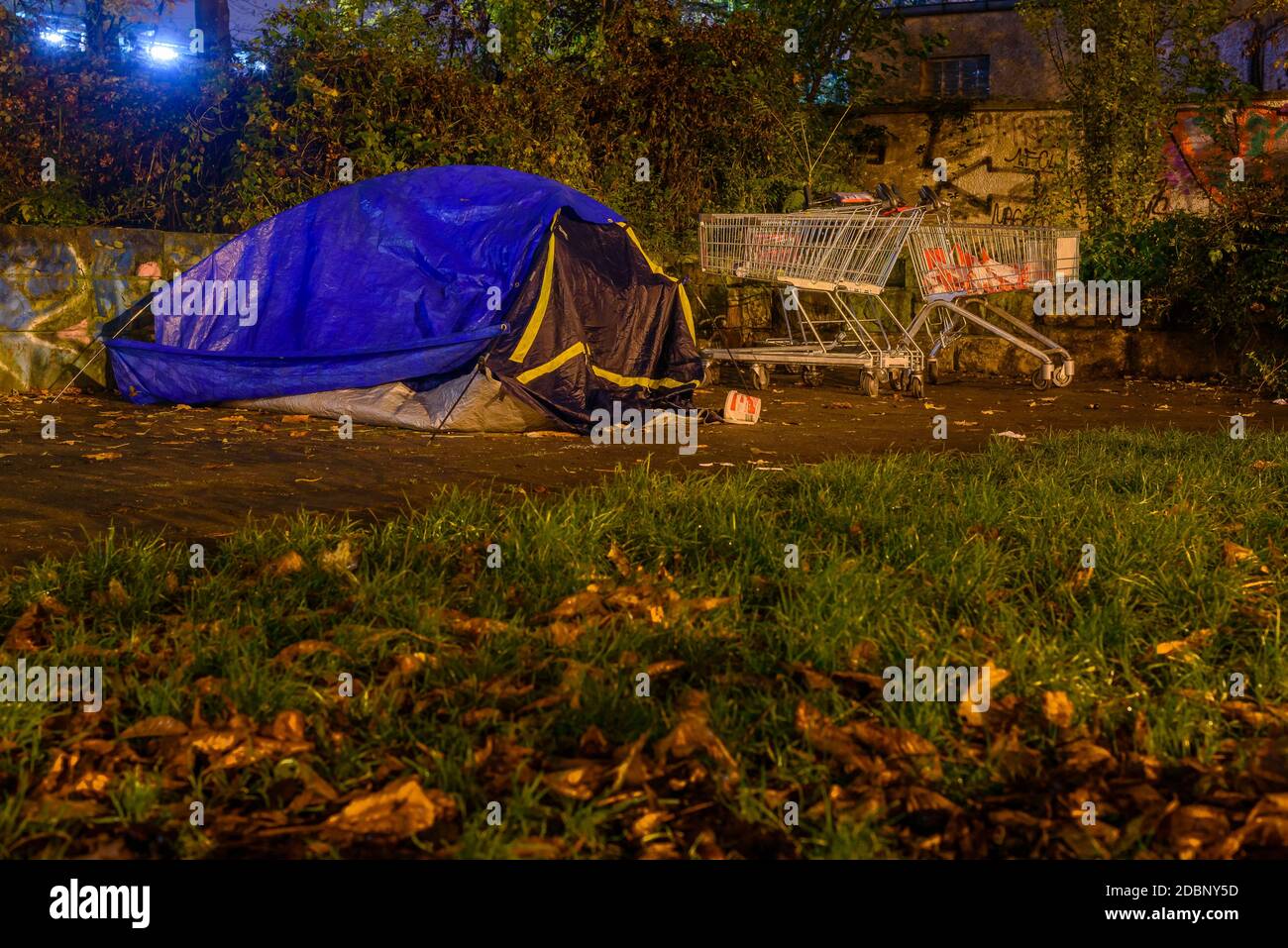 Tent of a homeless person in the city at night, shopping cart and a ...