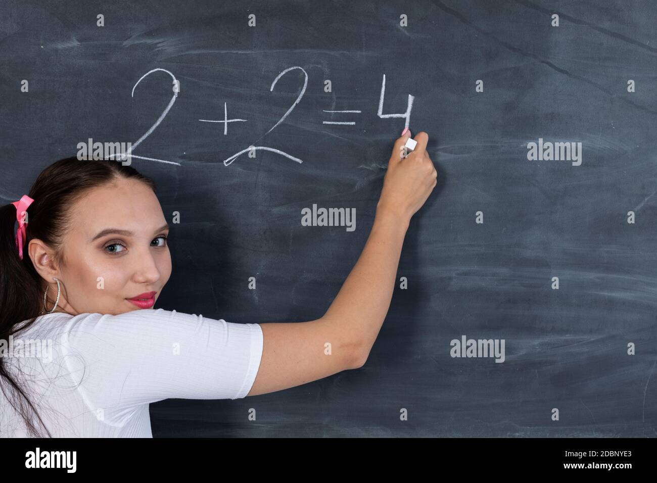 A young schoolgirl writes on the blackboard. School math lesson. He ...