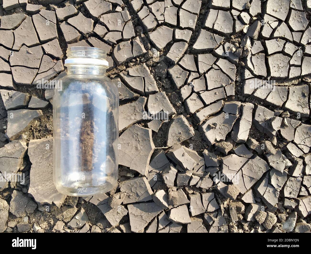 Empty bottle on dry ground at hot, arid day. Water deficit concept ...