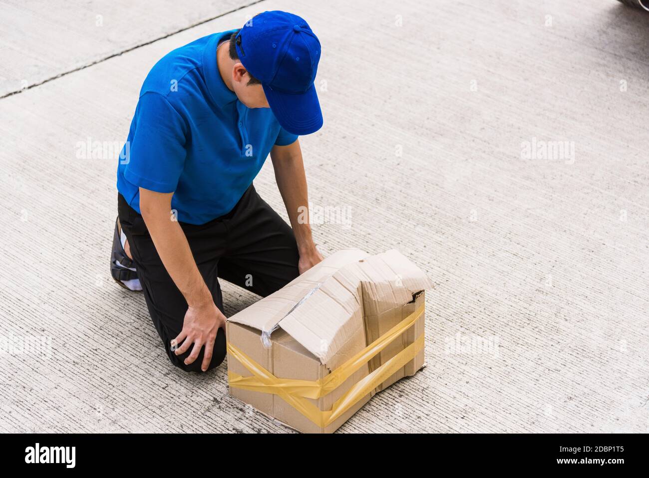 Asian young delivery man in blue uniform he emotional falling courier ...