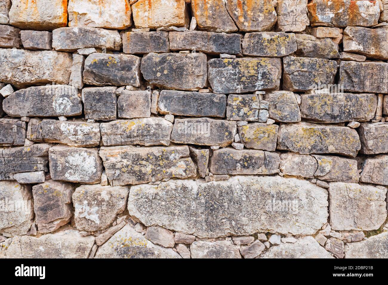 Wall of thick ancient rocks, rustic background of medieval construction ...