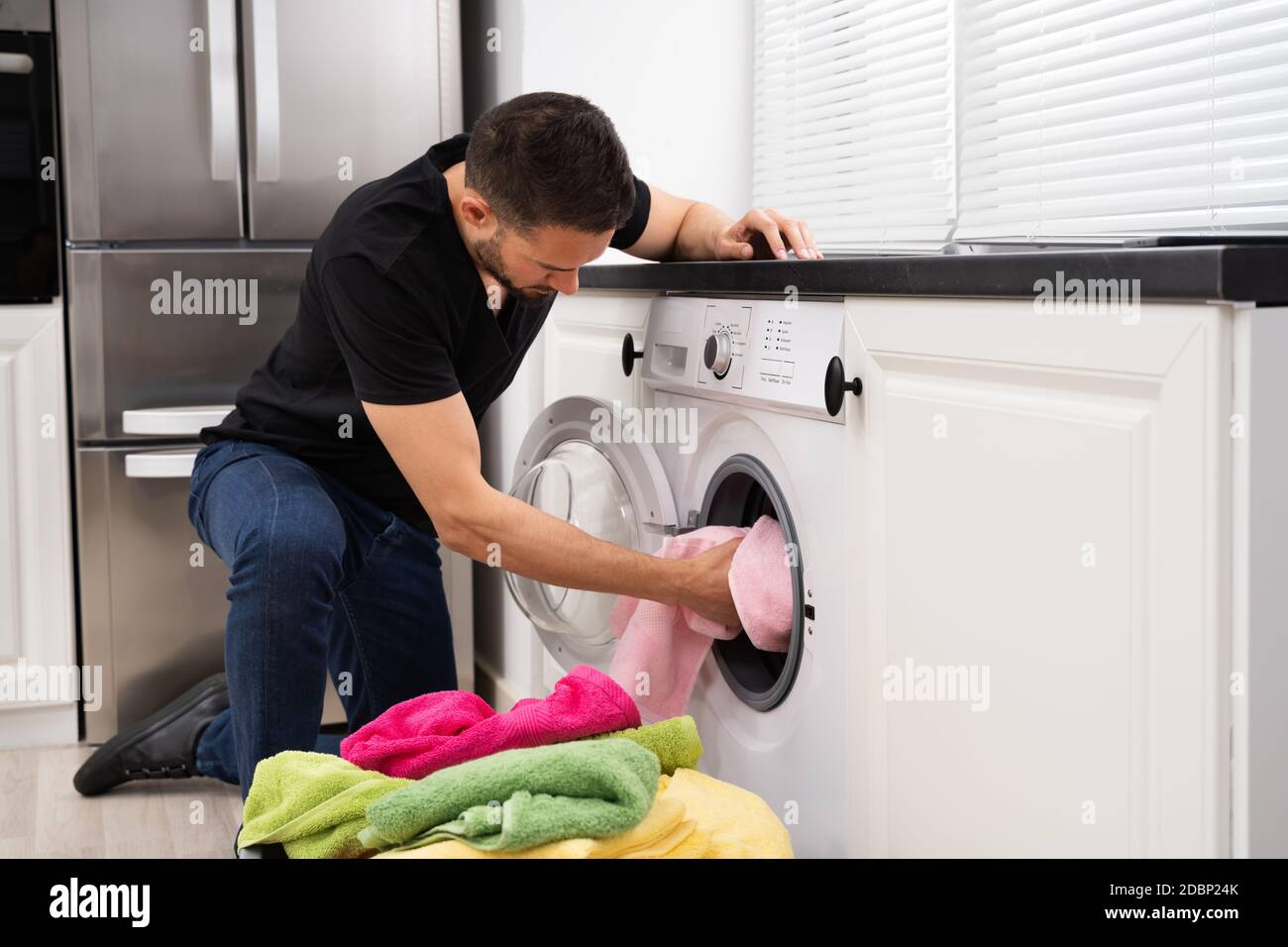 Man Loading Clothes Into Washing Machine In Kitchen Stock Photo - Alamy