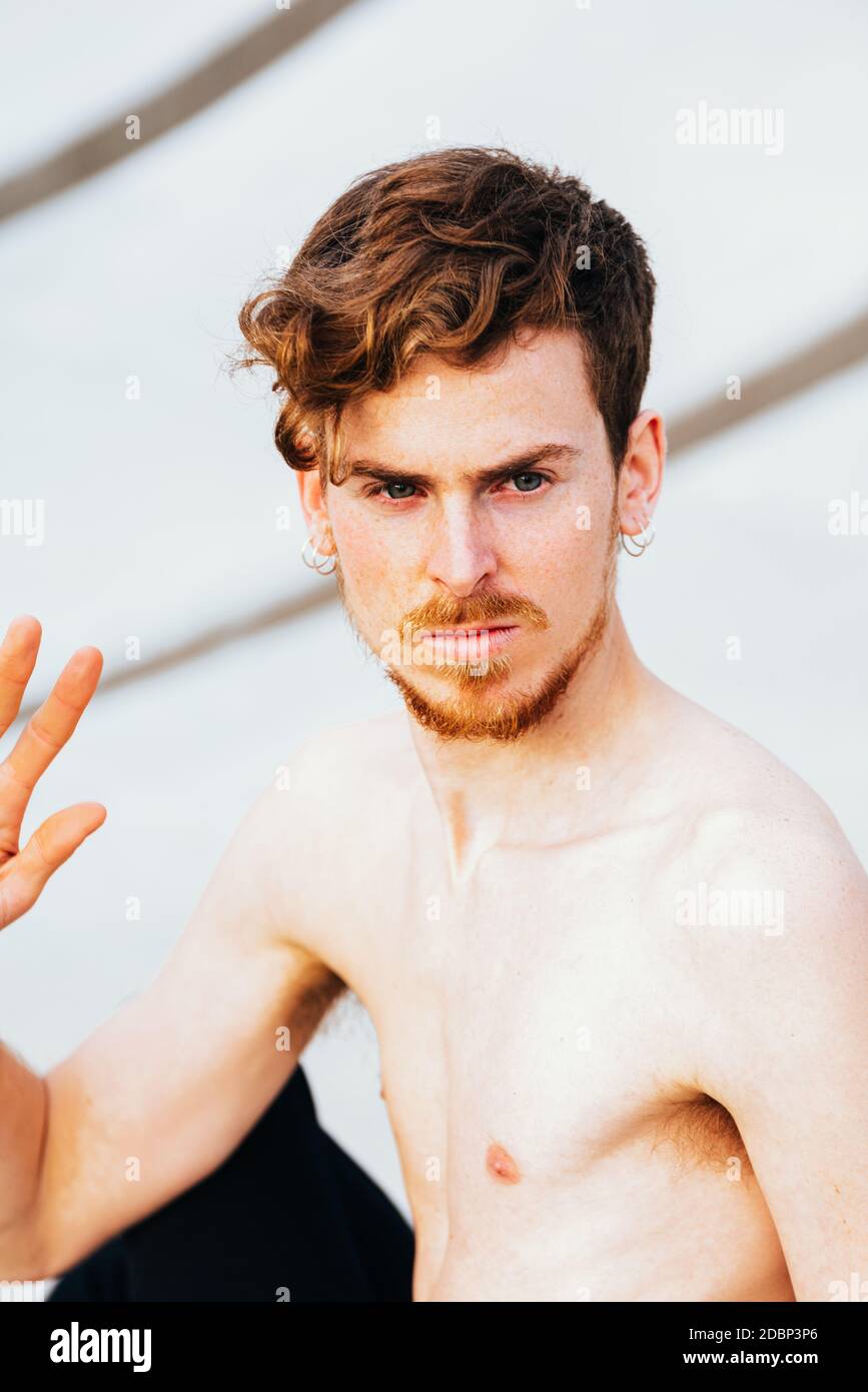Portrait of young red-haired man with freckles, shirtless exercising ...