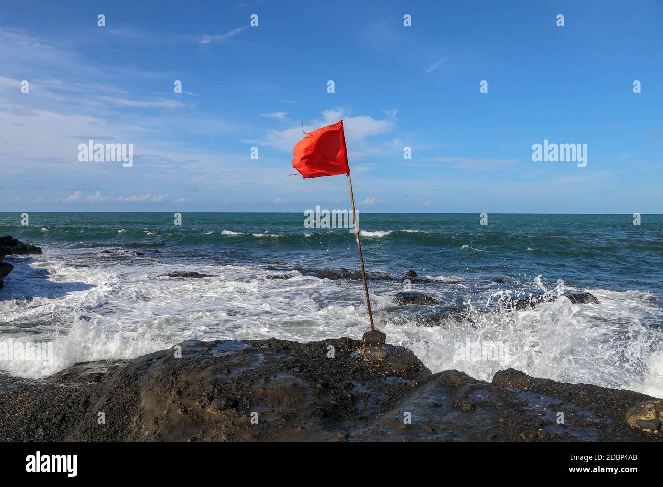 Red flag on a wooden flagpole flies on coast of Indian Ocean. Sign ...