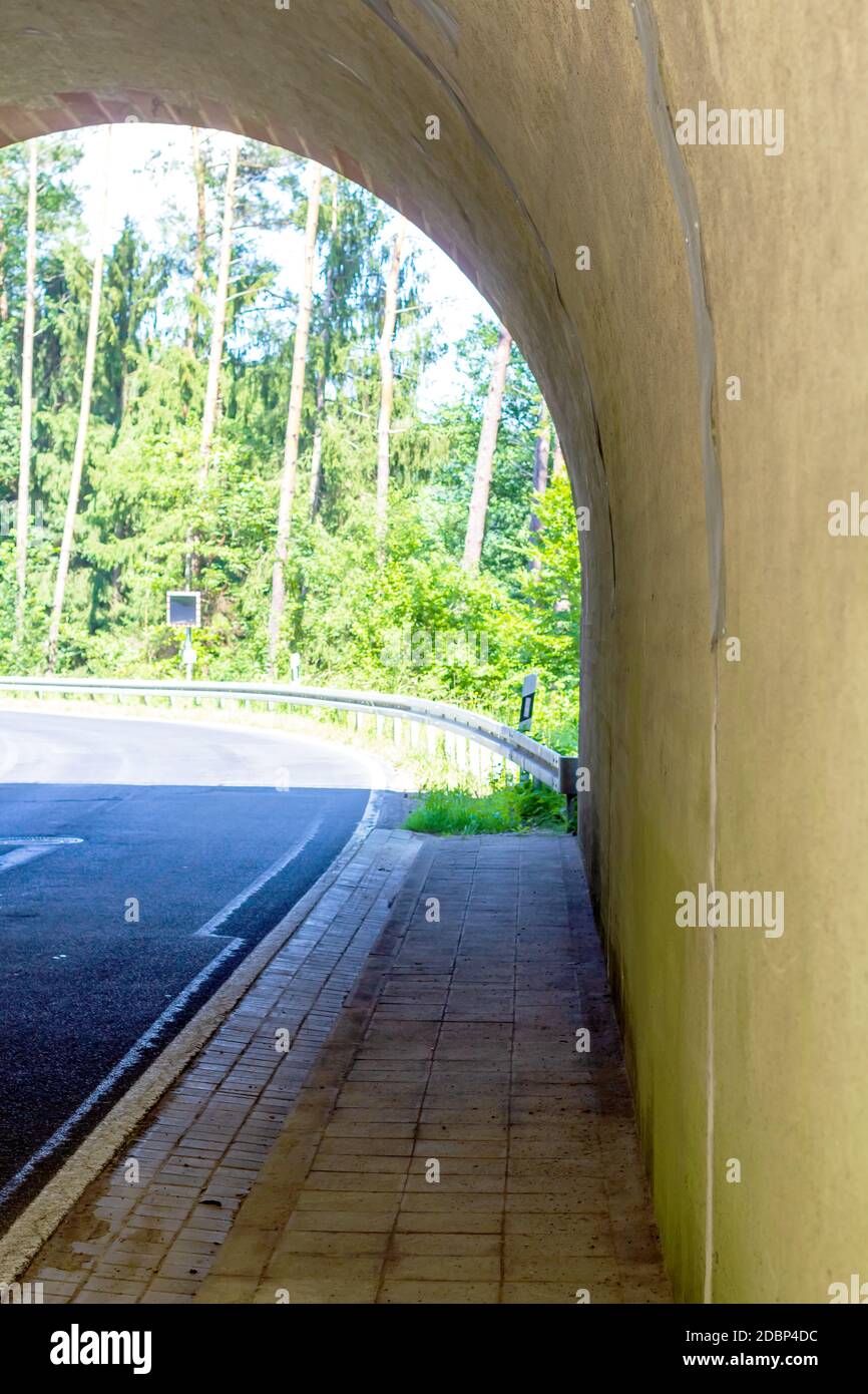 view through a railway tunnel, with focus on the gutter along the road ...