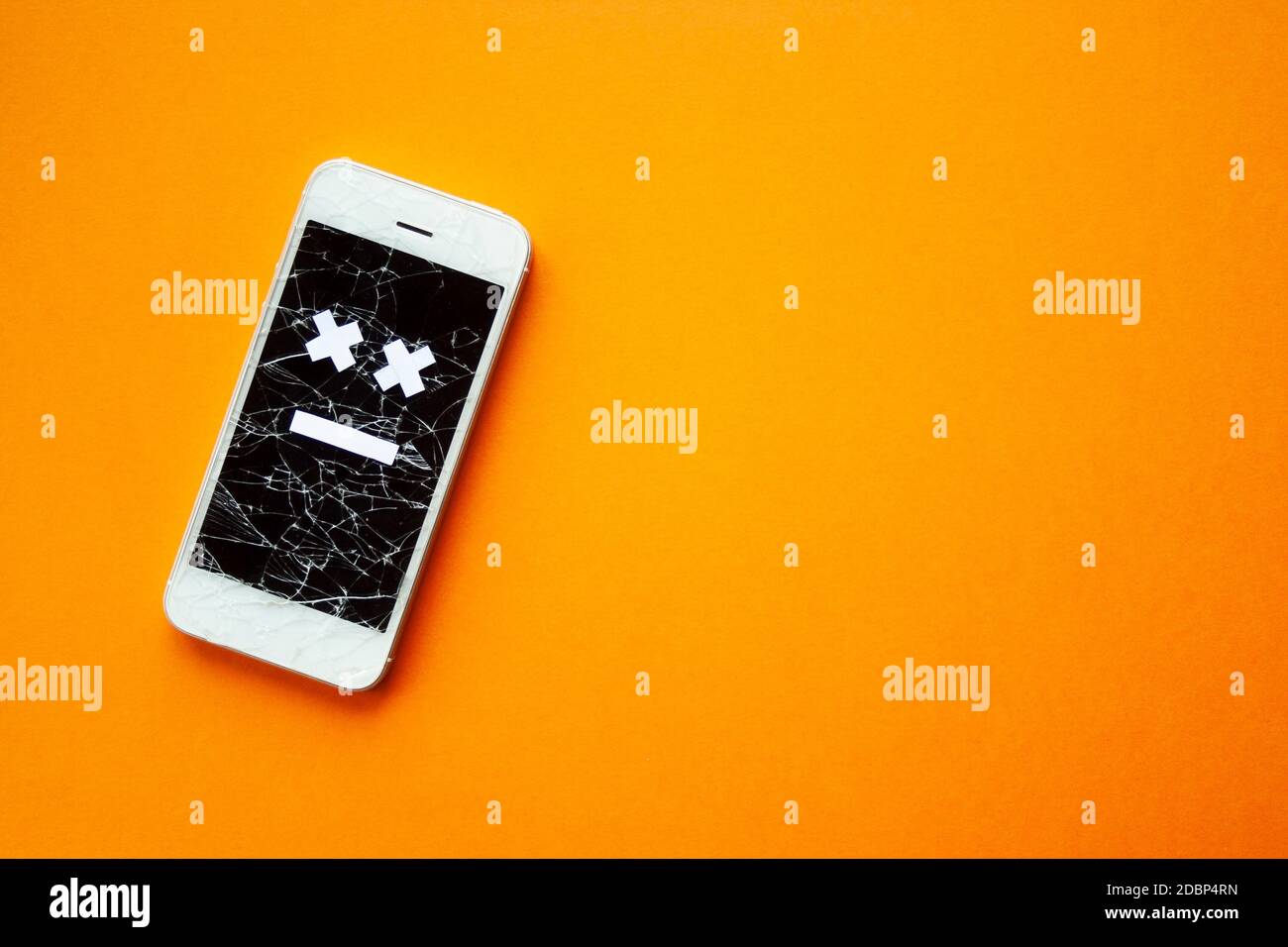 Broken smartphone with cracked destroyed screen on orange background ...