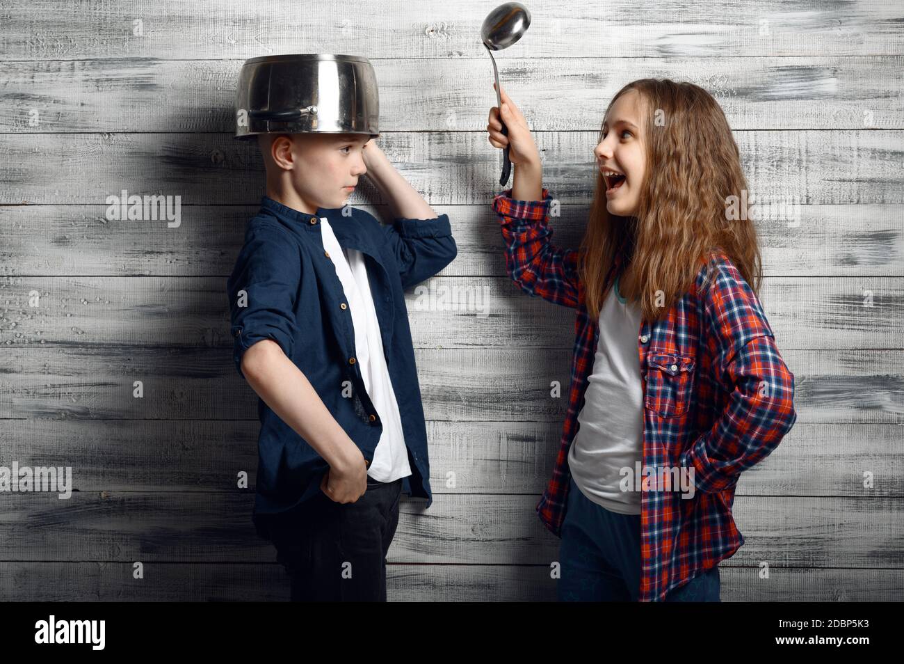 Little boy with a pot on his head and girl with the ladle in hand in ...