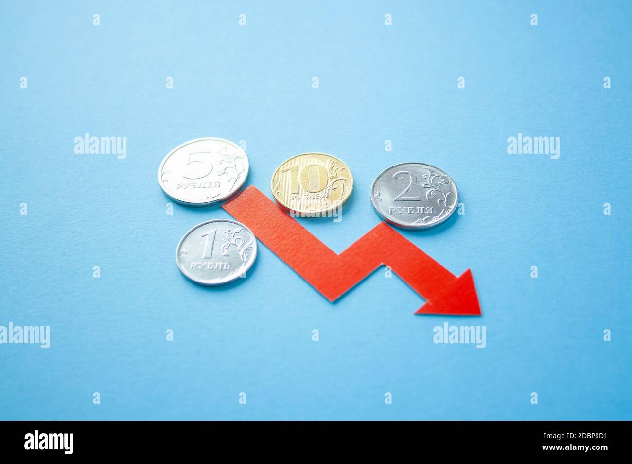 many rouble coins on blue background with red arrow down. exchange rate ...