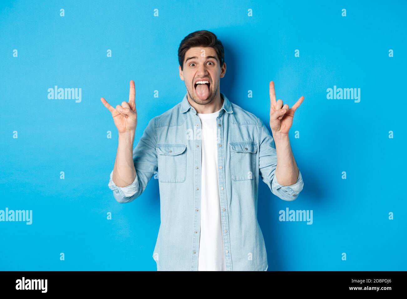 Cool guy having fun, enjoying concert, showing rock sign and tongue ...