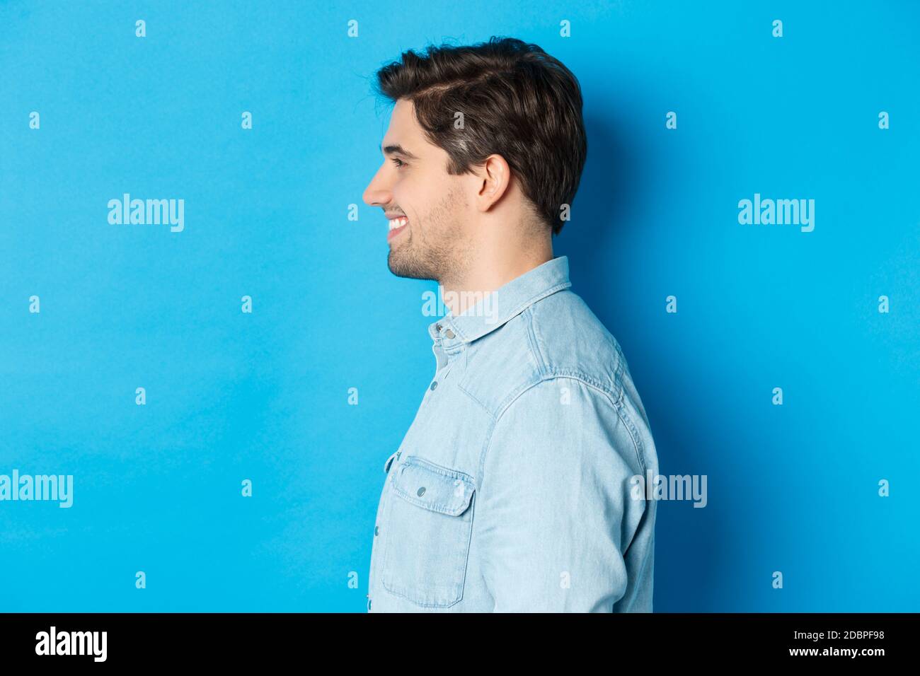 Profile of handsome young man looking left, smiling happy, standing ...