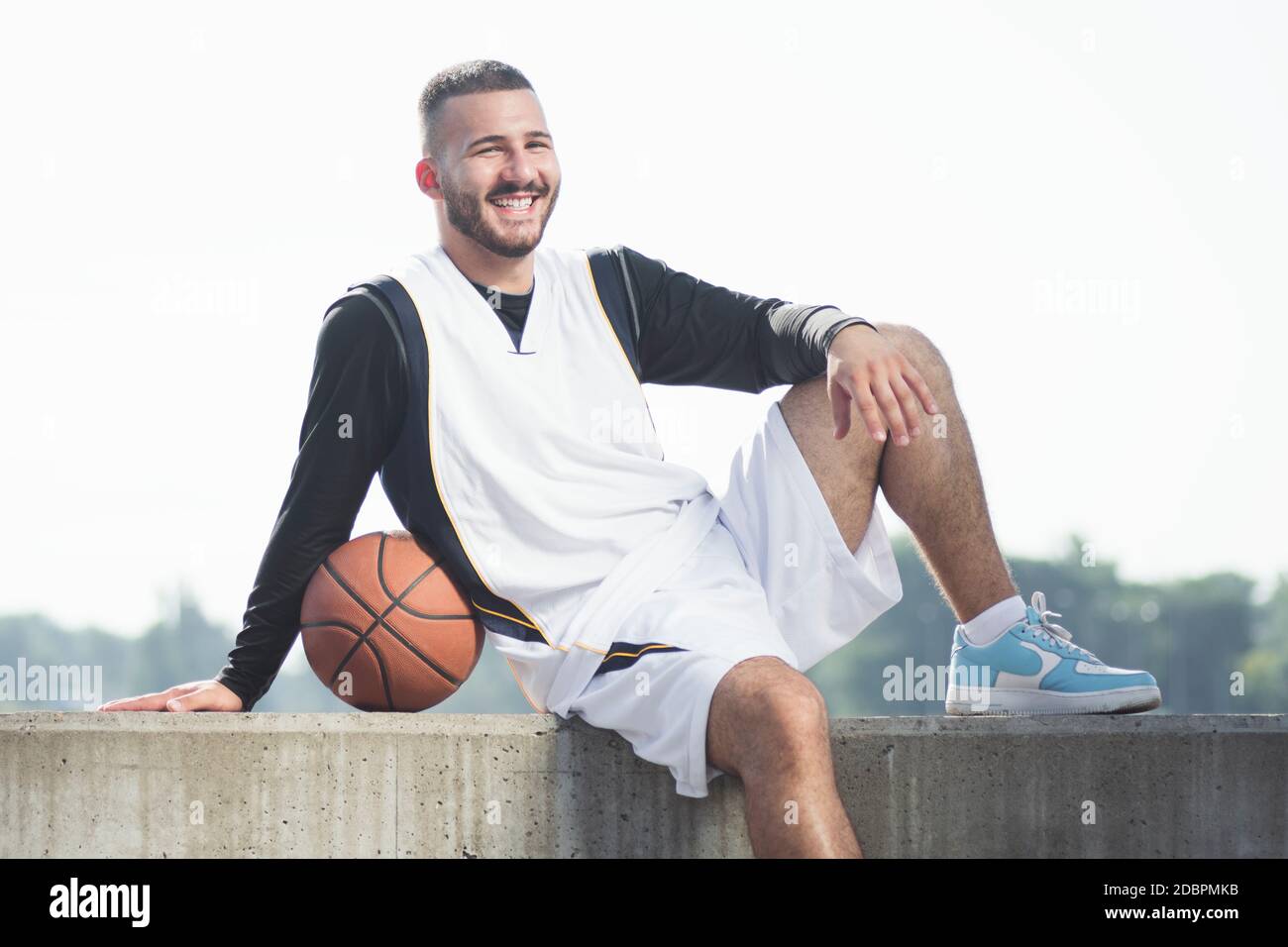 The smiling handsome young basketball player in sportswear with ...