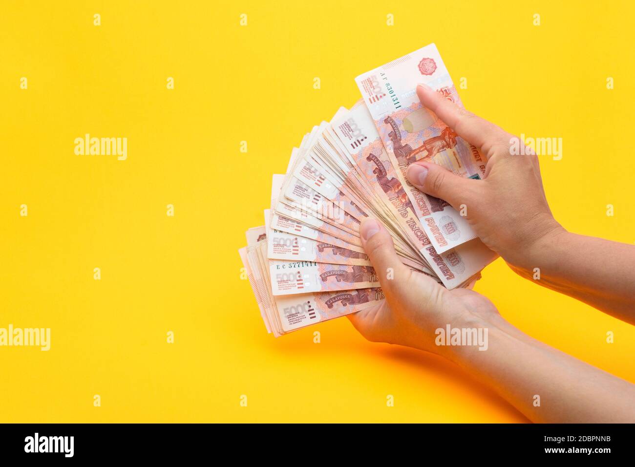 Hands count money in a bundle of notes, yellow background Stock Photo ...