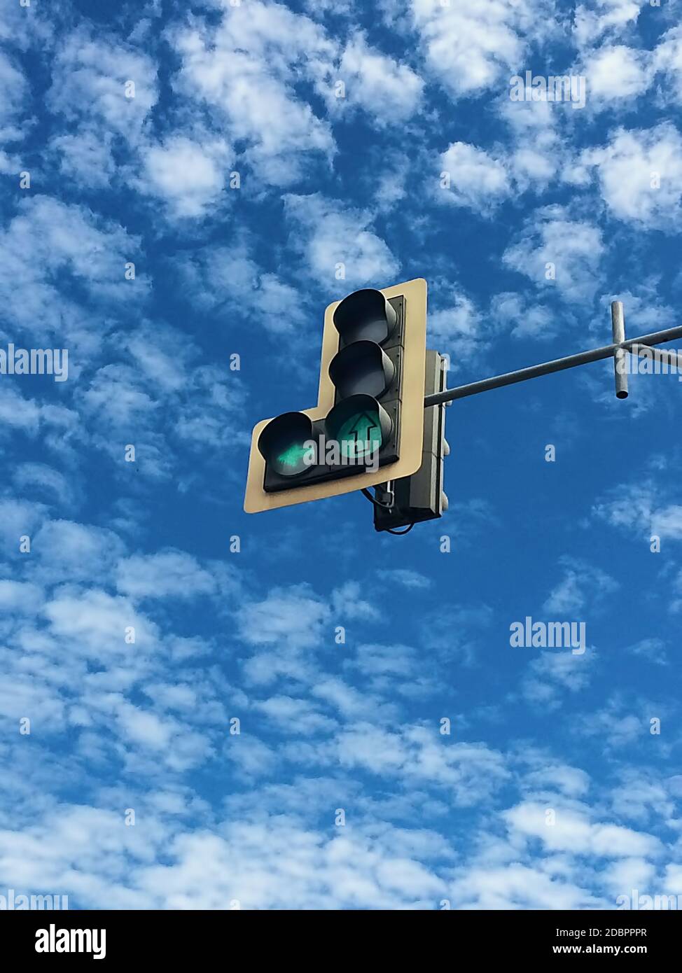 Traffic lights against a blue sky and lots of white clouds. The green ...