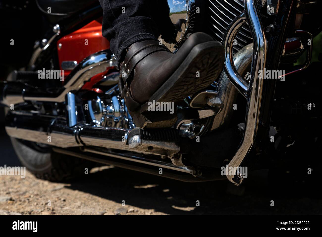Biker riding a motorcycle. Bottom view of the legs in leather cowboy ...