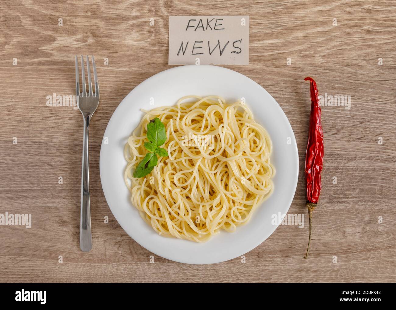Spaghetti with a sprig of basil and chili pepper as a fake news concept ...