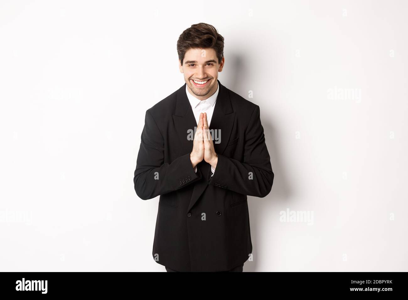 Portrait of handsome man in black suit, being grateful, saying thank ...