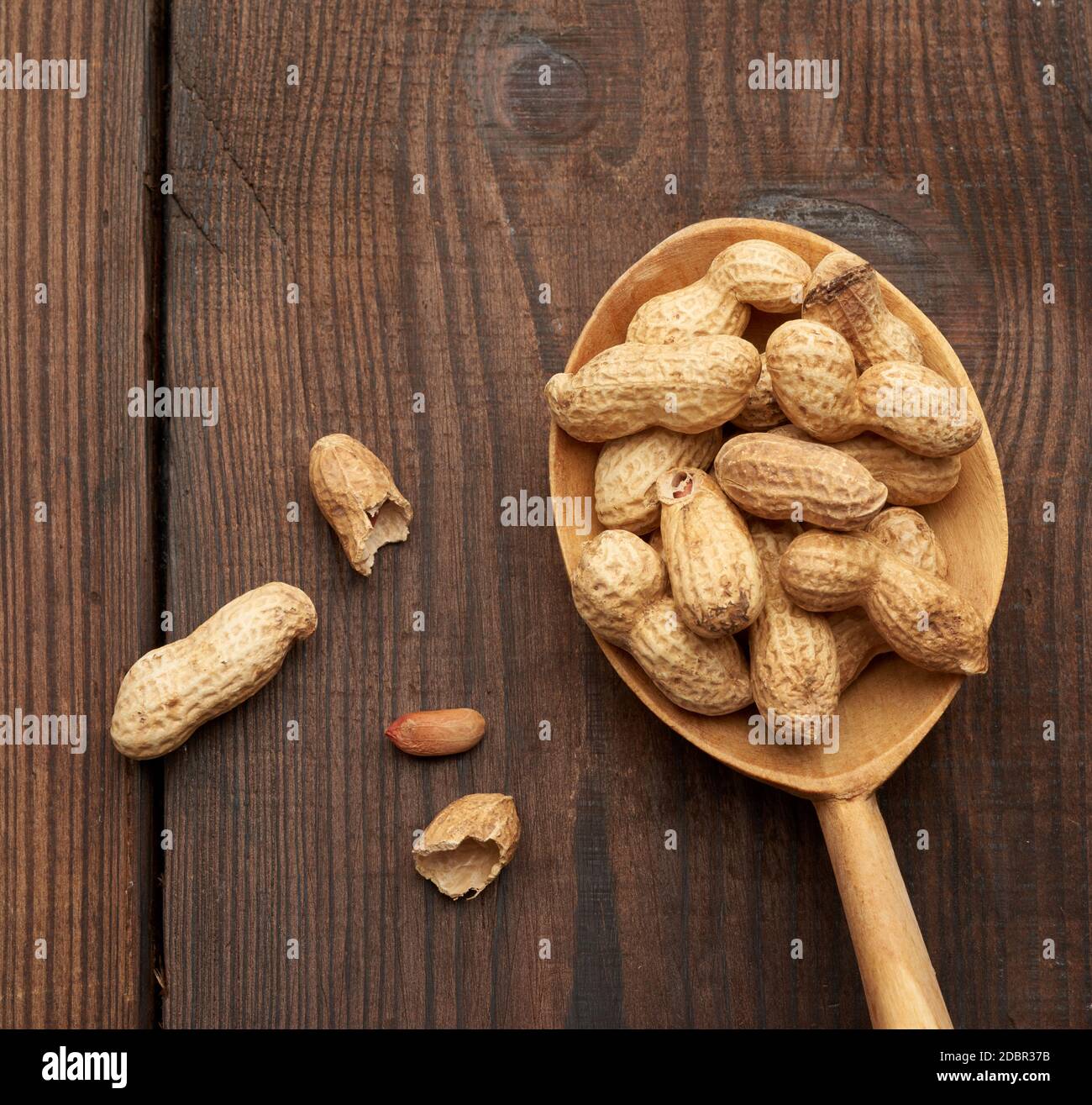 unpeeled peanuts in a wooden spoon on the table, tasty and healthy ...