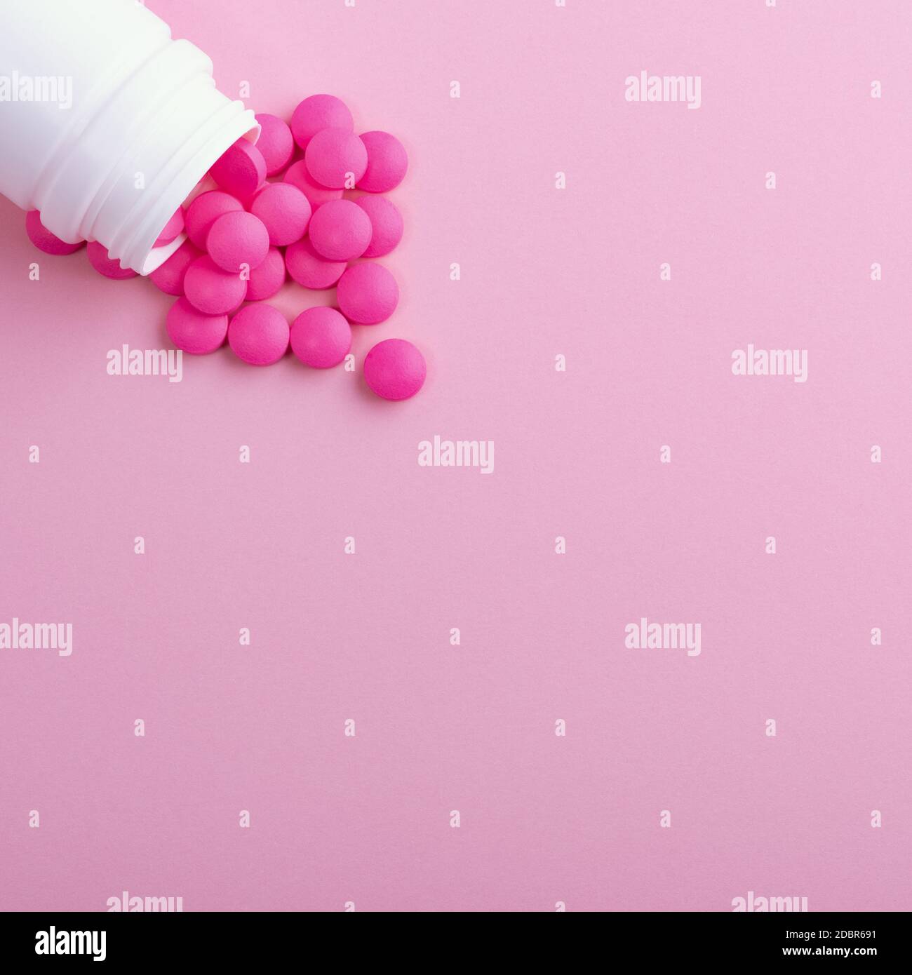 Pills of bright pink color are scattered from a white medical jar ...