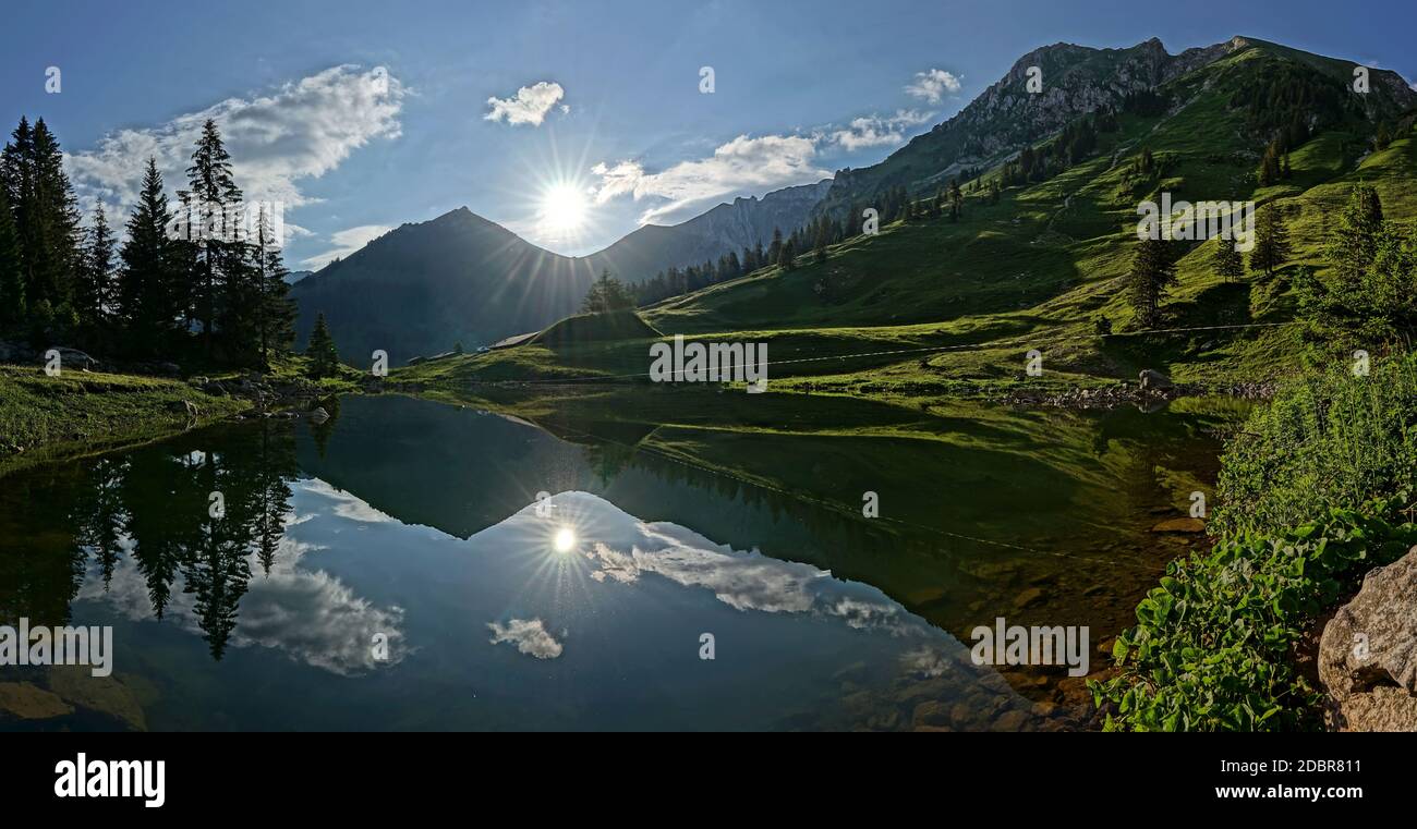 The first rays of sun are reflected in the mountain lake Stock Photo ...