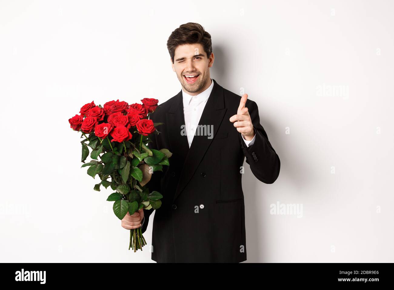 Image of handsome romantic guy in black suit, holding bouquet of roses ...