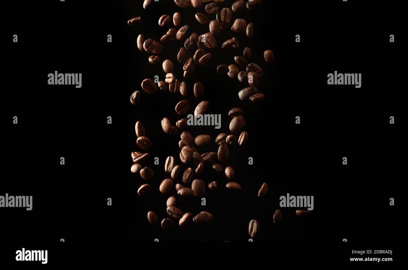 flying roasted coffee grains on a black background, fragrant ...