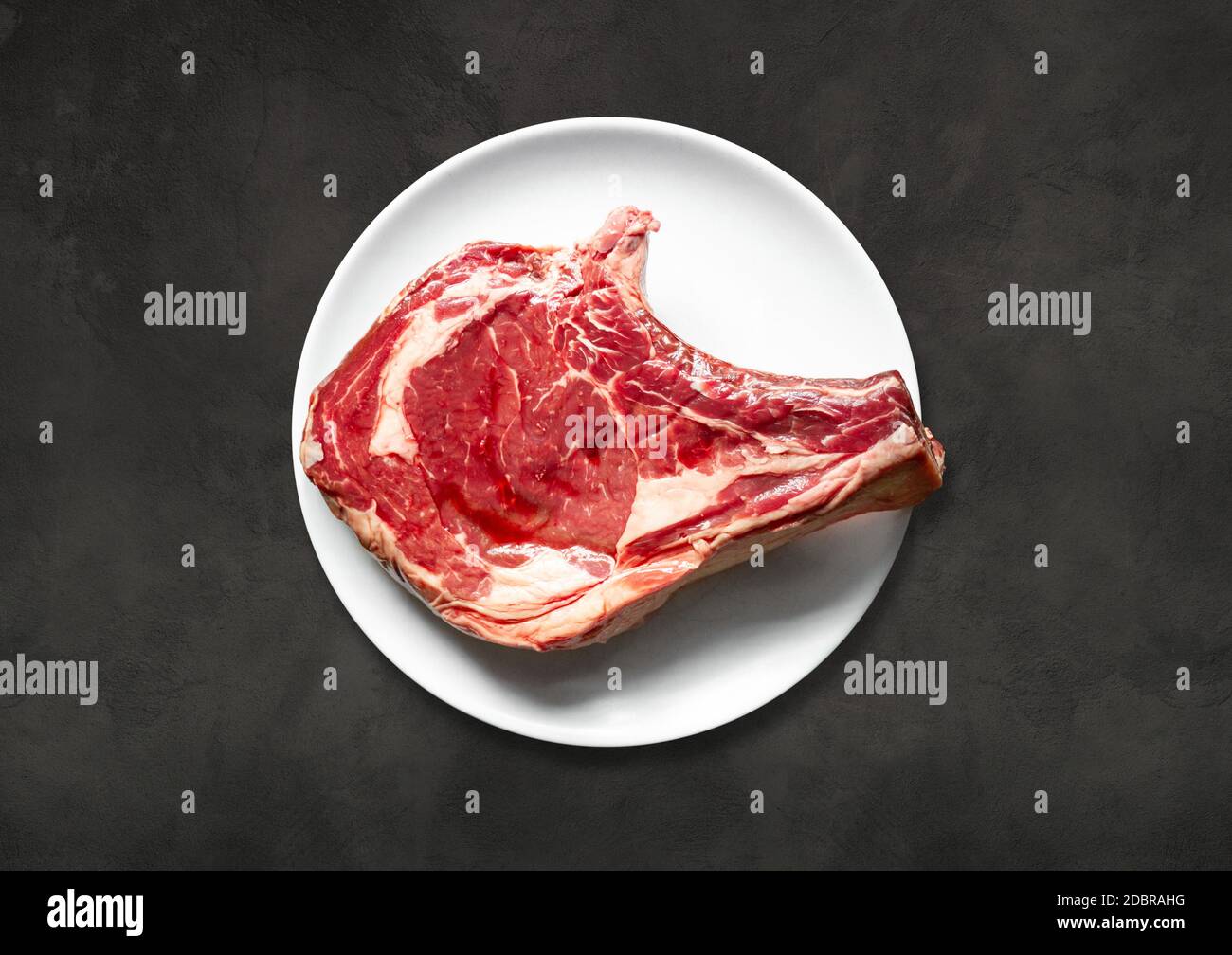 Raw beef prime rib on a plate, concrete background. Top view Stock ...
