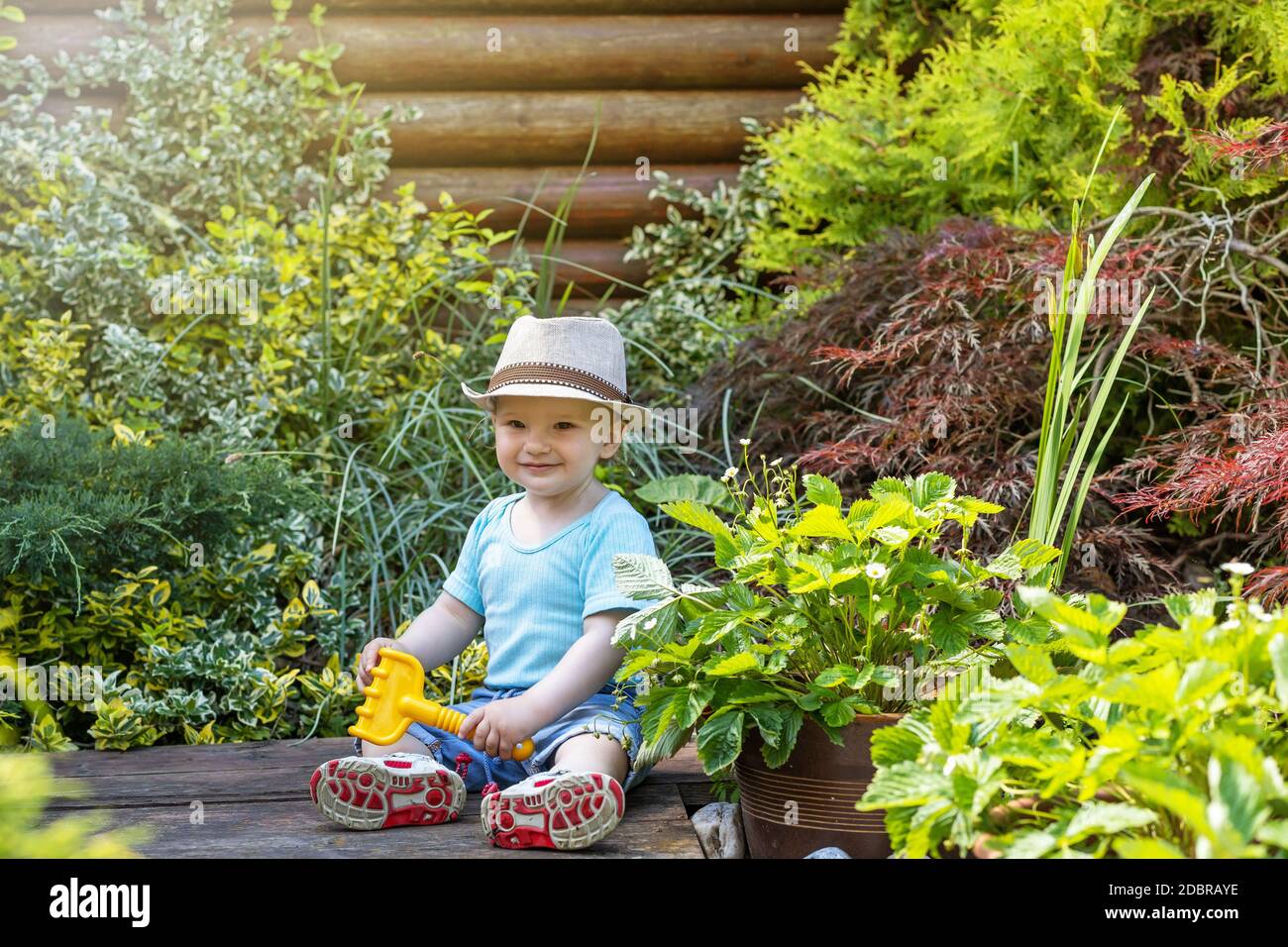 Cute little baby boy is playing with yellow baby rake sitting in the ...