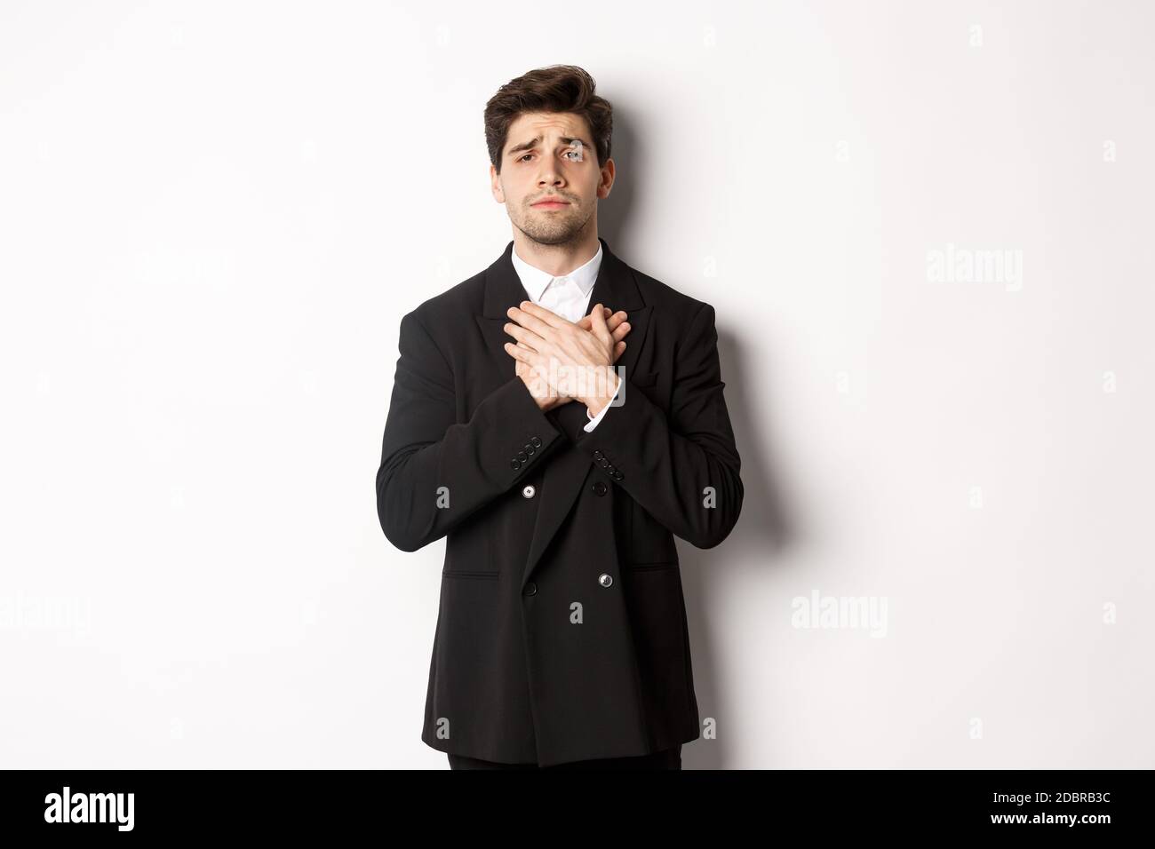 Portrait of touched and compassionate guy in suit, holding hands on ...
