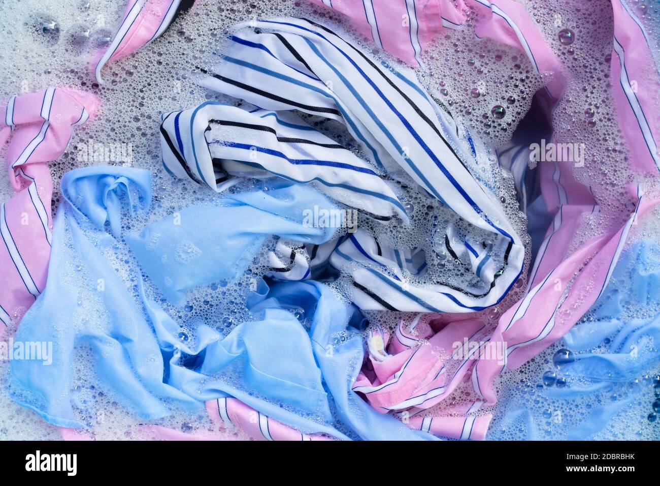 Top view of color clothes soak in powder detergent water dissolution ...