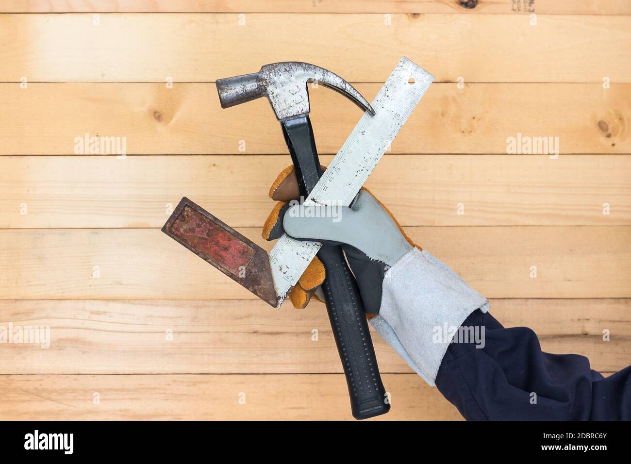 Working hand in glove holding iron ruler and hammer with wall wood ...
