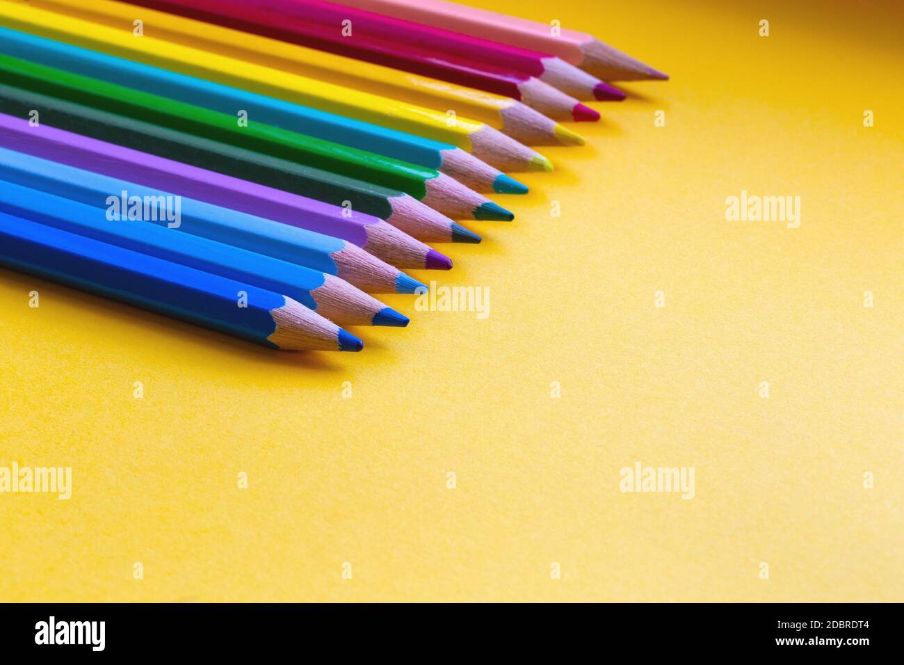 Colored pencils in Rainbow colors in a row on orange background, retro ...