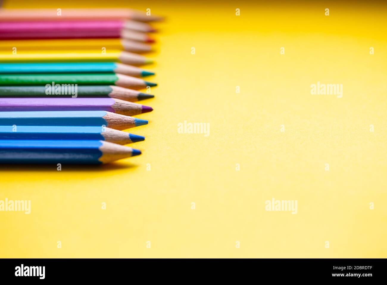 Colored pencils in Rainbow colors in a row on orange background, retro ...