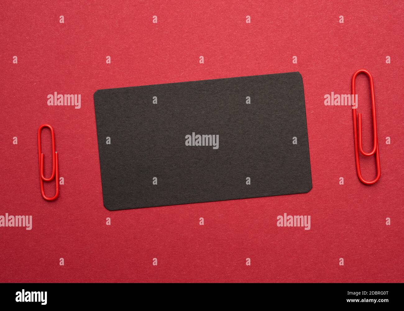 black paper cardboard business card and red metal paper clip on a red ...