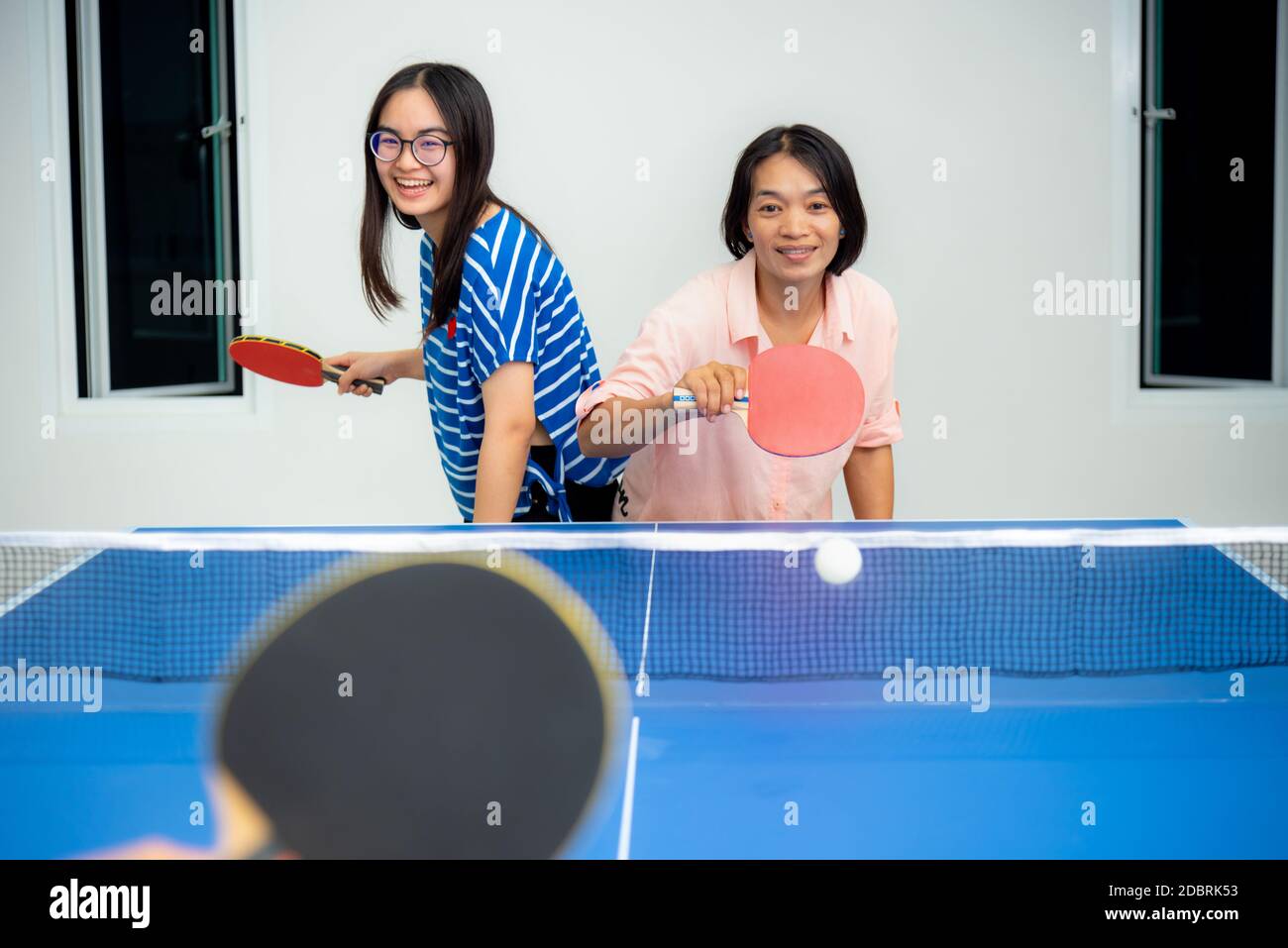 Asian family fun playing table tennis or Ping pong indoor together ...