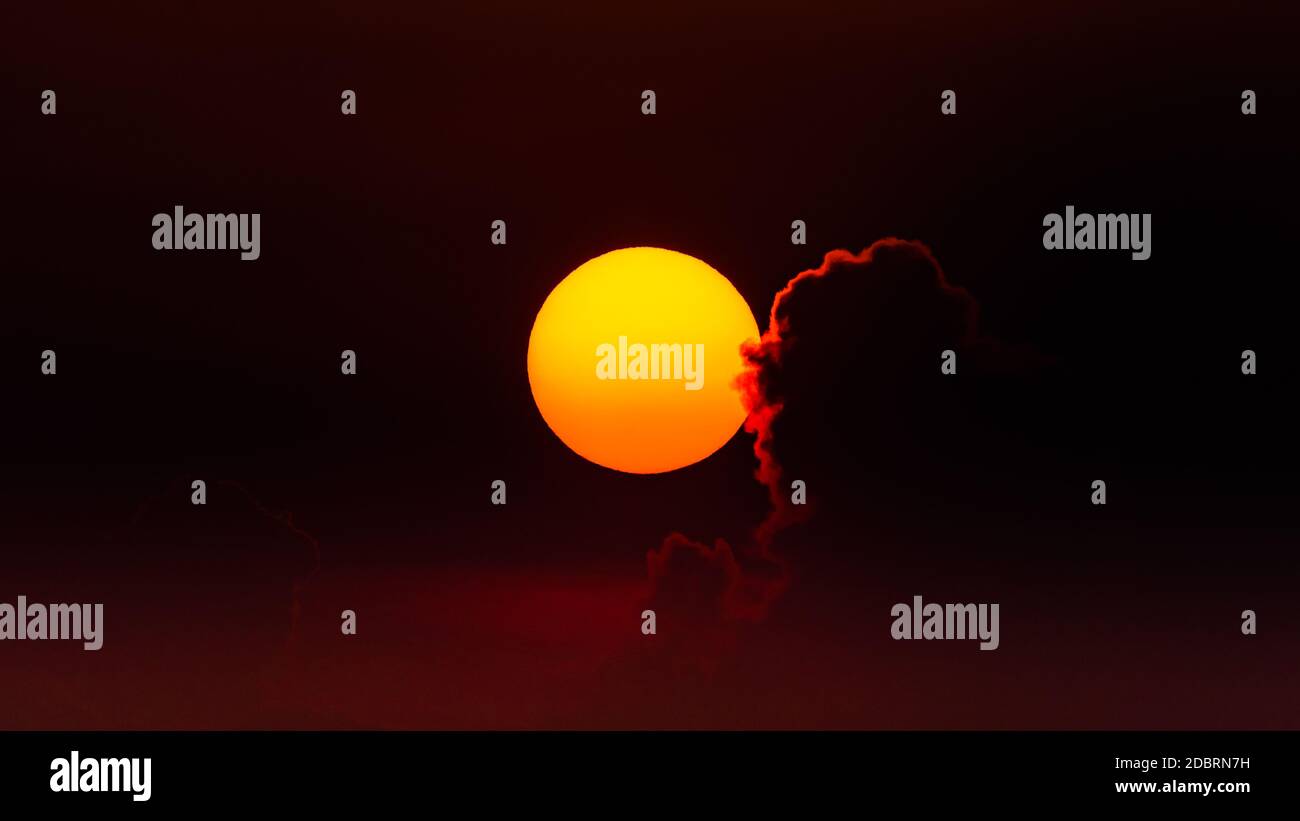 Orange - yellow Sun at sunset against red sky with back lit cloud Stock ...