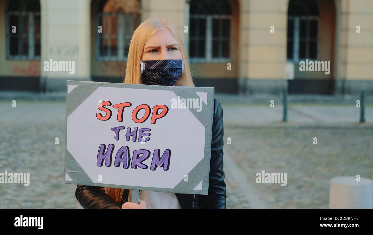 Blonde woman in protective mask protesting to stop harm by holding ...