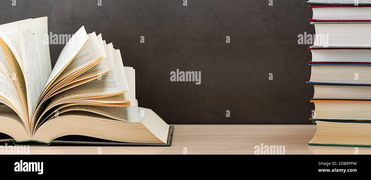 A large, thick hardcover book is lying on a light wood table. The book ...
