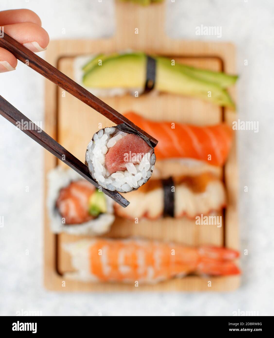 Hand taking roll with chopsticks from a plate top view close up Stock ...