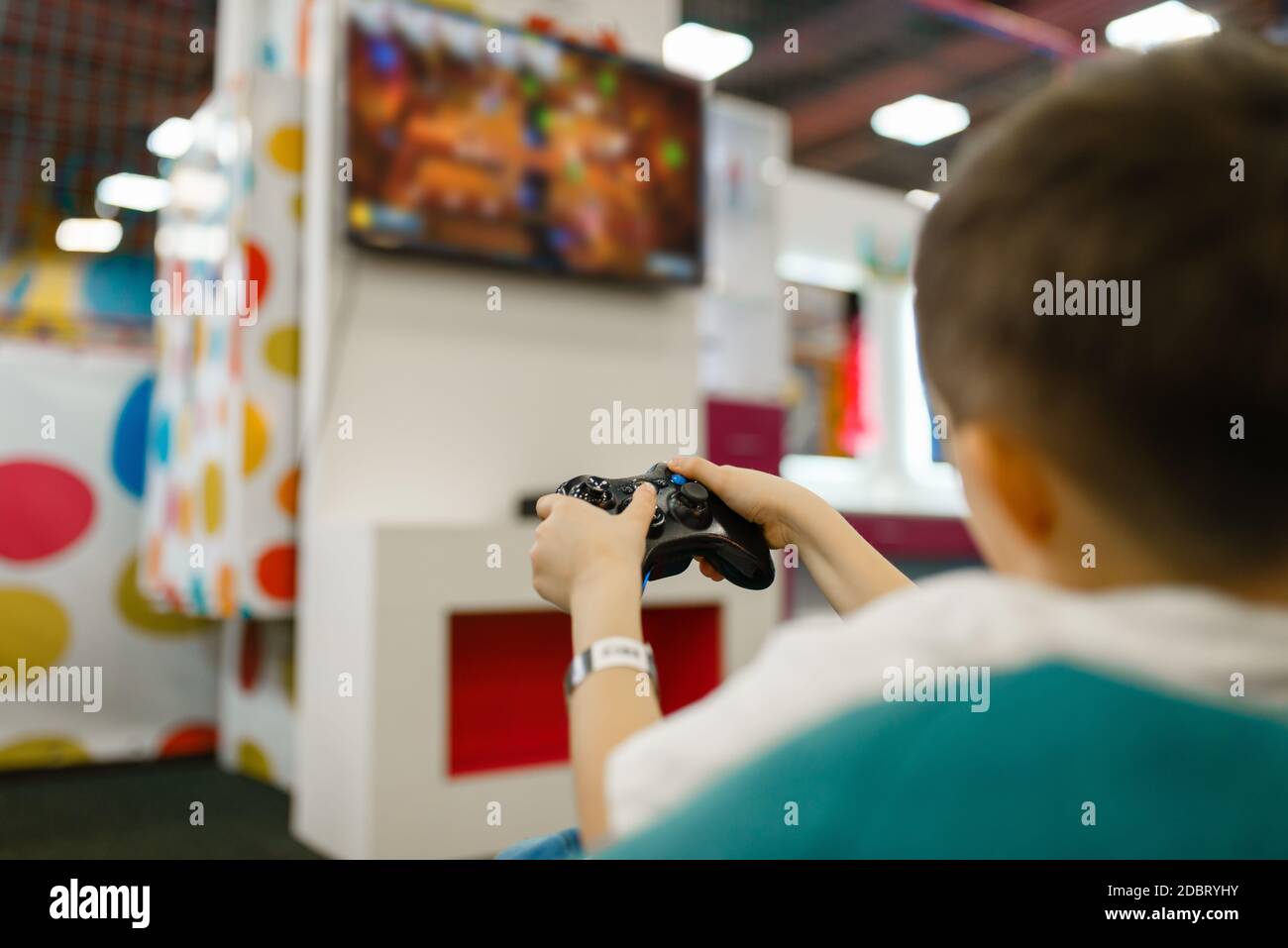 Boy plays a game console in the entertainment center. Male child ...