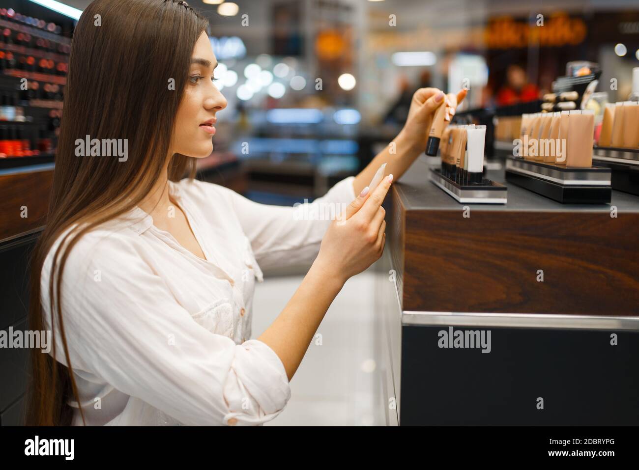 Beautiful woman at the shelf in cosmetics store, side view. Buyer at ...