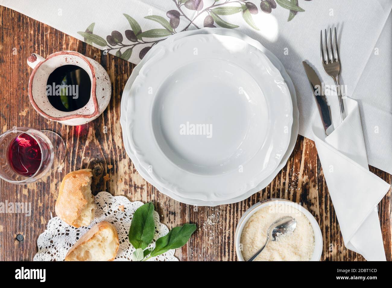 Traditional Italian table set with plate, cutlery, rustic bread, wine ...