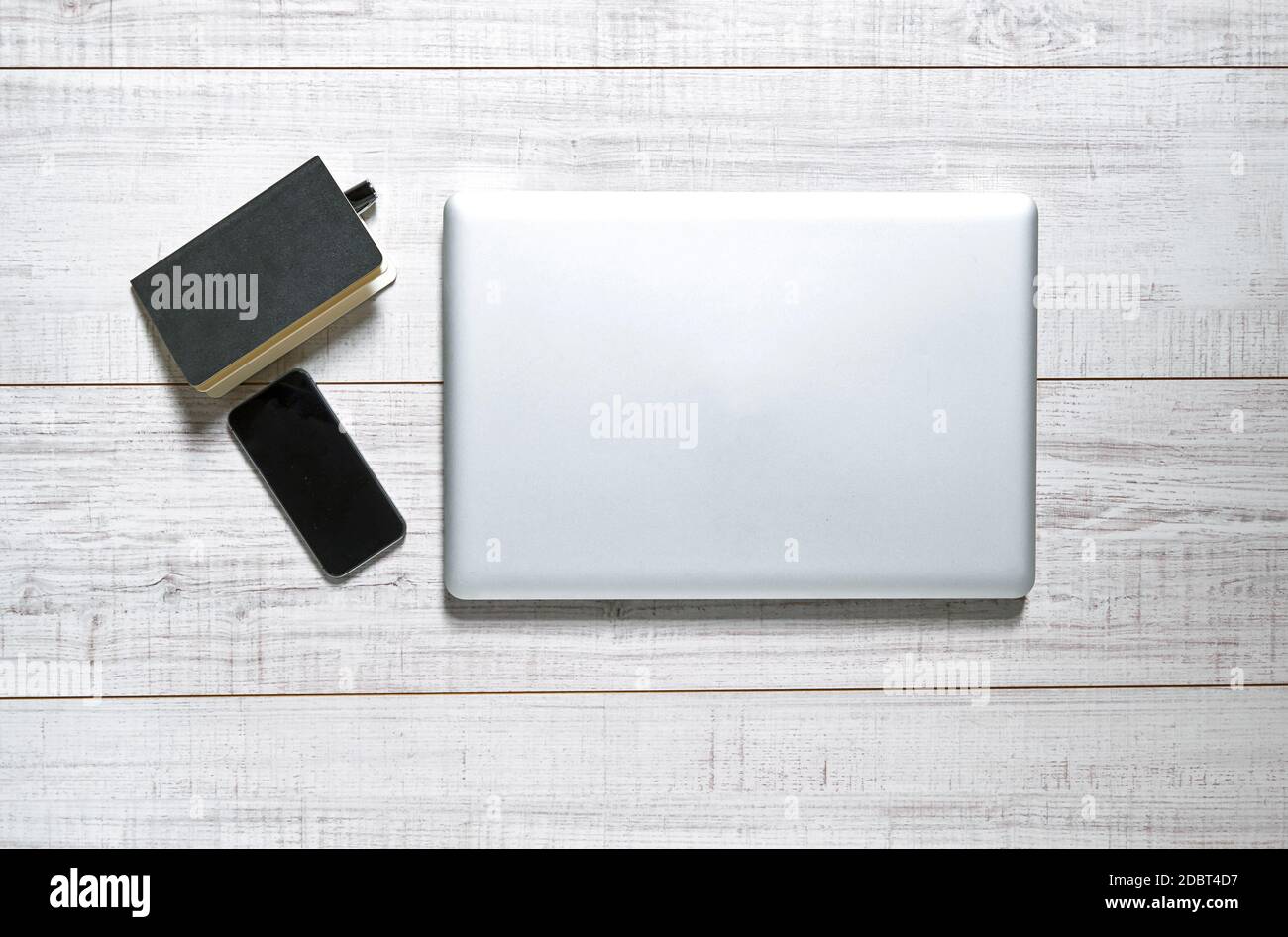 View of a wooden table with a laptop, mobile, notebook and a pen on it ...