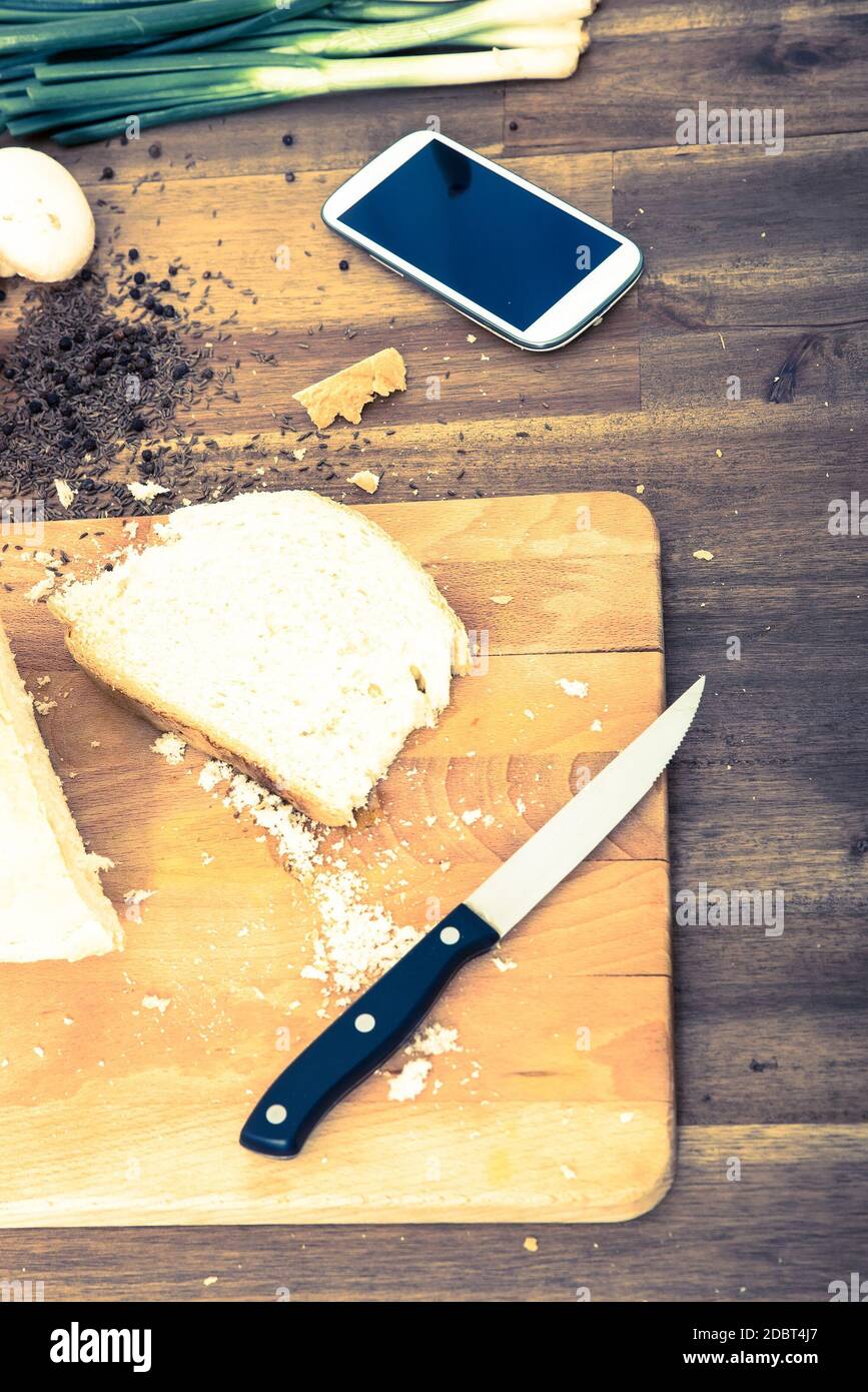 A smartphone lying in a natural kitchen with white bread, spices ...