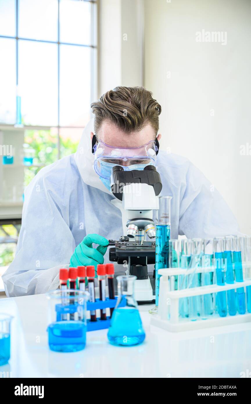 Male scientist wearing protection suit working with Microscope and many ...