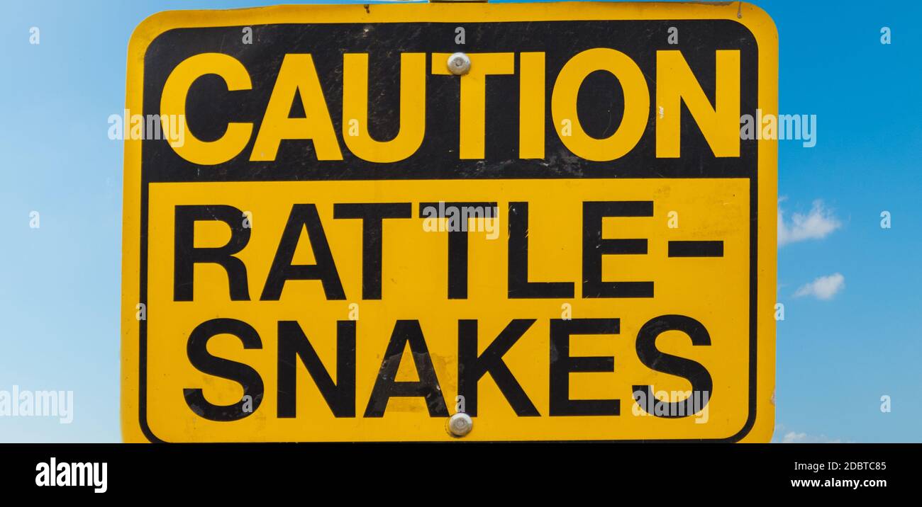 CAUTION RATTLE SNAKES signs under a blue sky Stock Photo - Alamy