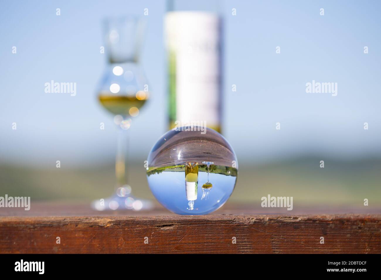 Crystal ball on wooden table with defocused bottle and filled glass in ...