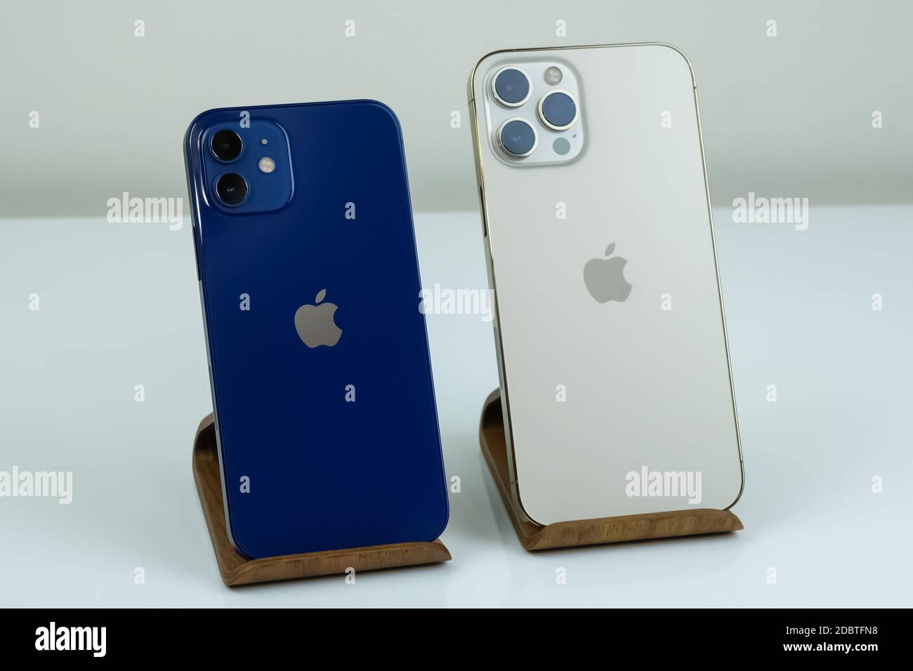 iPhone 12 Pro Max in Gold next to iPhone 12 in Blue on a white desk ...