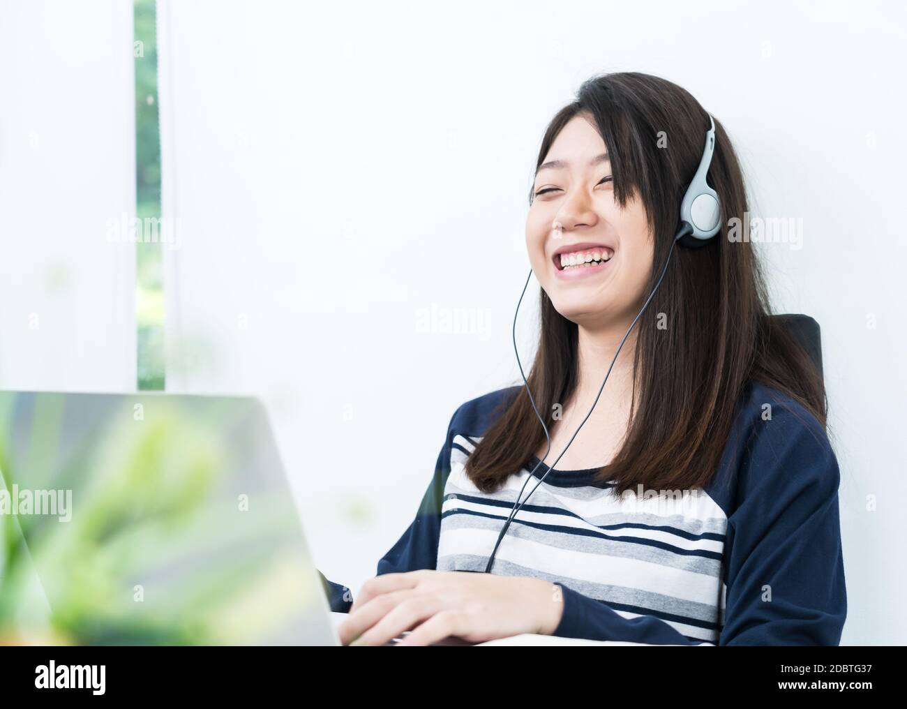 Young female student sitting in living room and learning online using ...