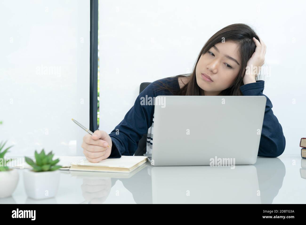 Young female student sitting in living room and learning online using ...